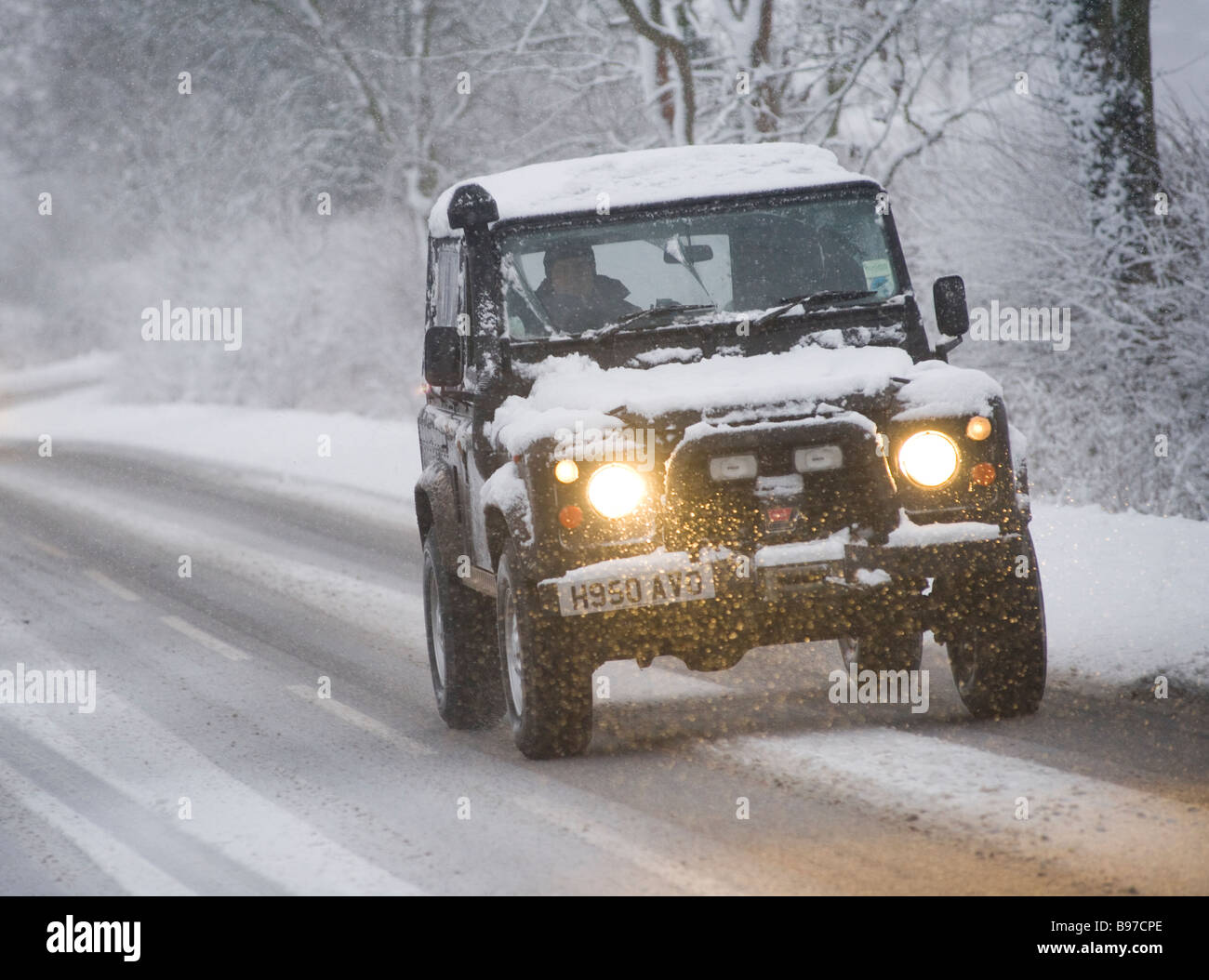 Lone 4x4 Land Rover driving down a snow covered road in the countryside ...