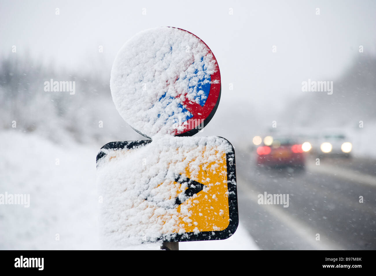 Road signs covered in snow with traffic passing by on a winters day in ...
