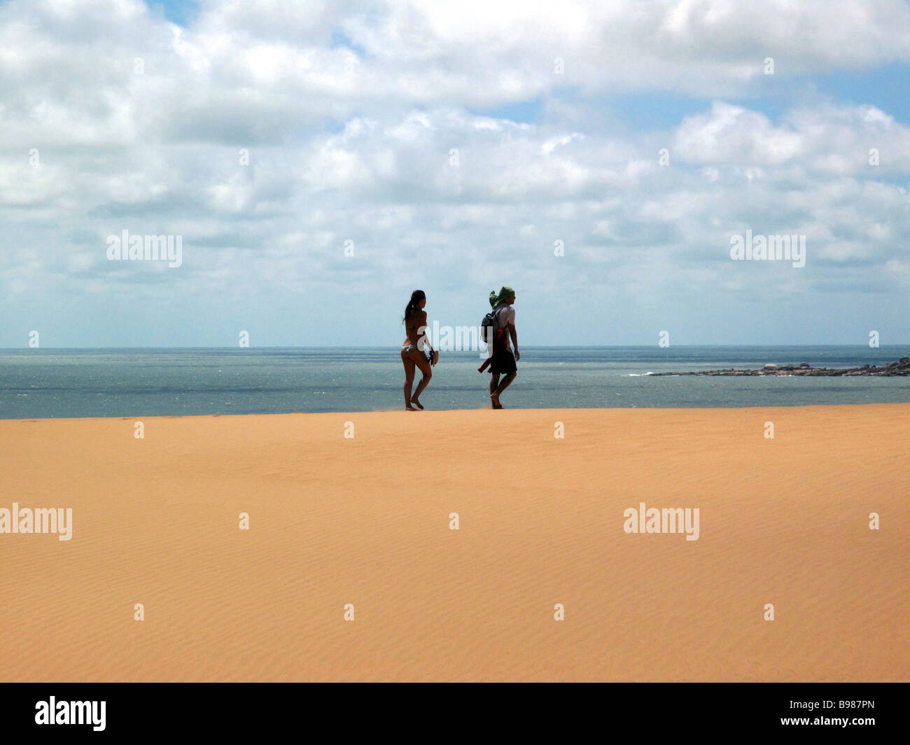 Man and woman walking on a sand dune near the sea Stock Photo - Alamy
