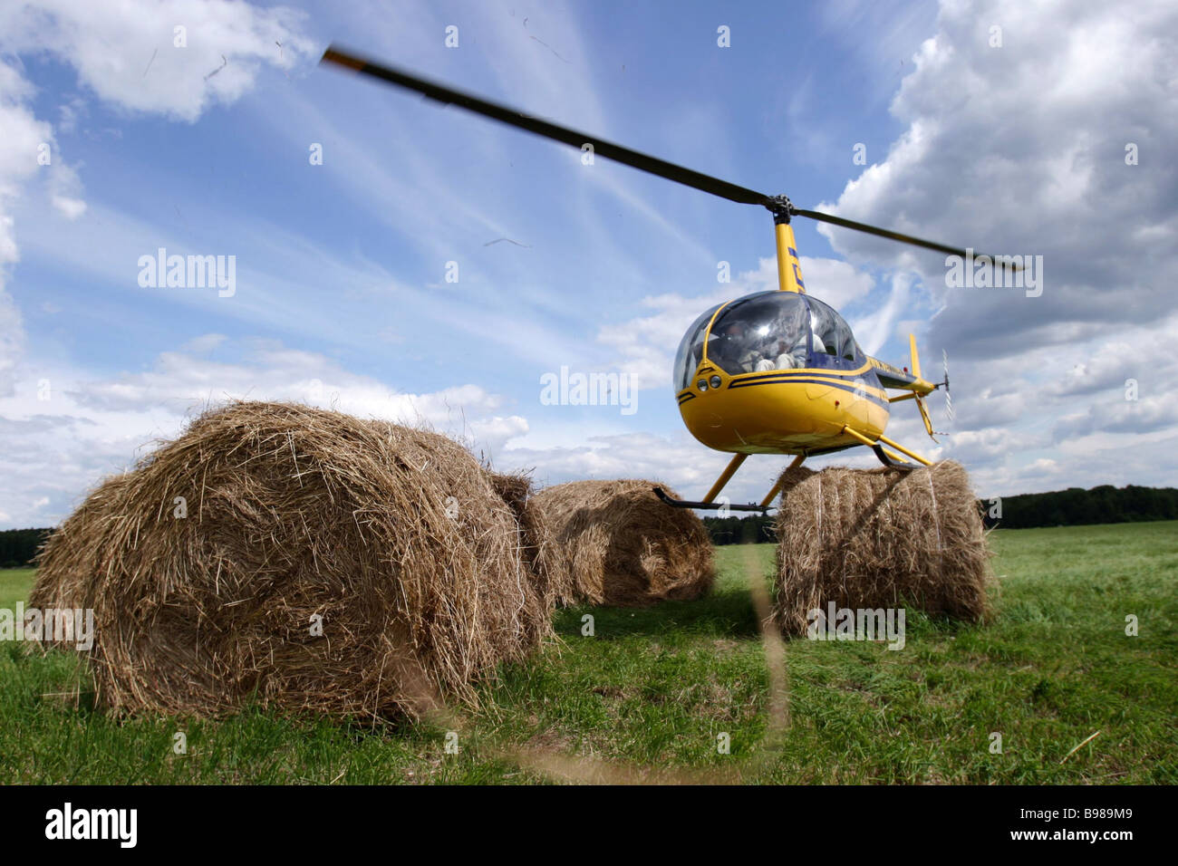 A helicopter flying above a field with sheaves Stock Photo - Alamy