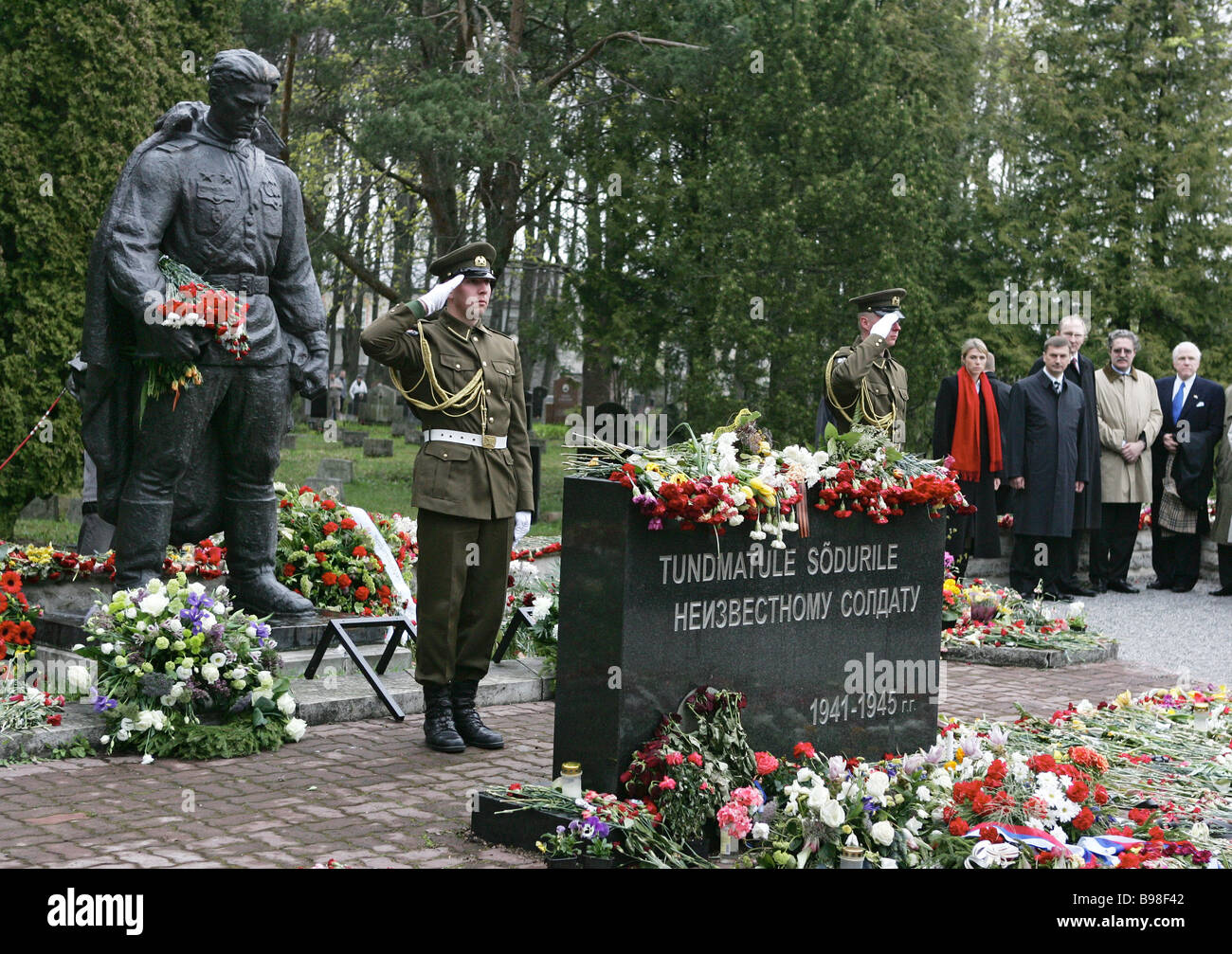 Laying flowers at the Bronze Soldier monument at a military cemetery in ...