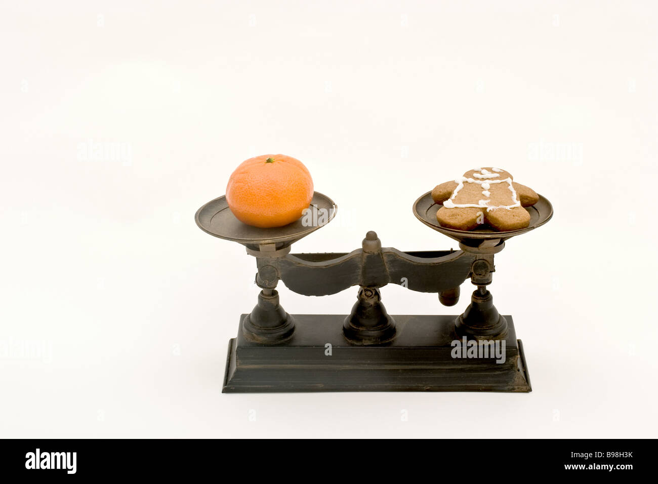 Balance scale with oranges on one side and a gingerbread cookie on the ...
