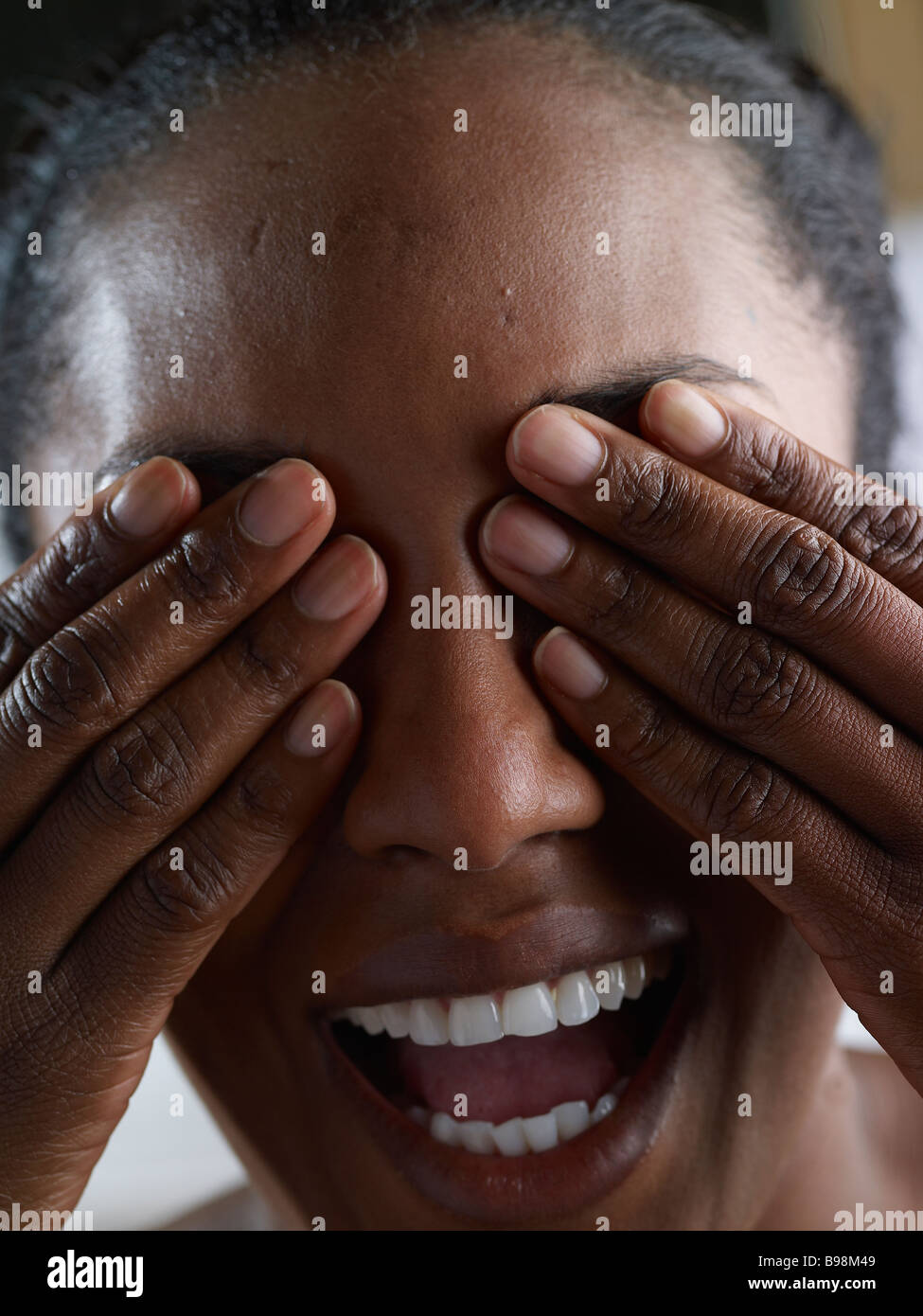 Black women holding hands over eyes laughing Stock Photo - Alamy