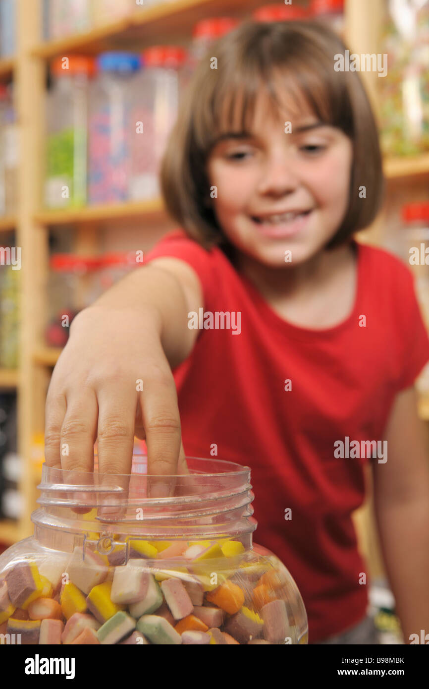 young girl grabbing sweets from a jar in a shop Stock Photo - Alamy
