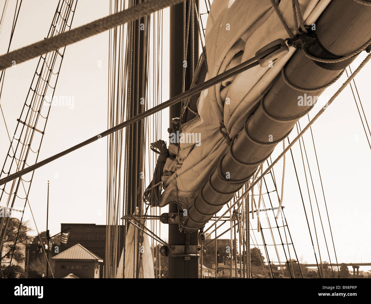 sepia view of the shore through the rigging furled sails and yardarm of ...