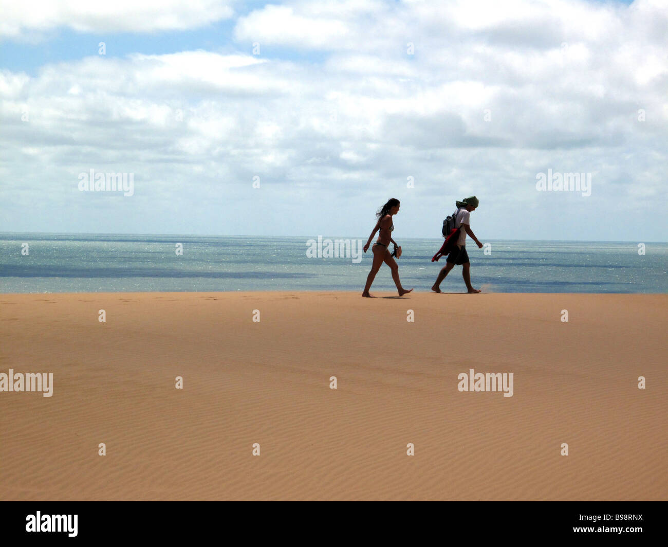 Man and woman walking in a sand dune near the sea Stock Photo - Alamy