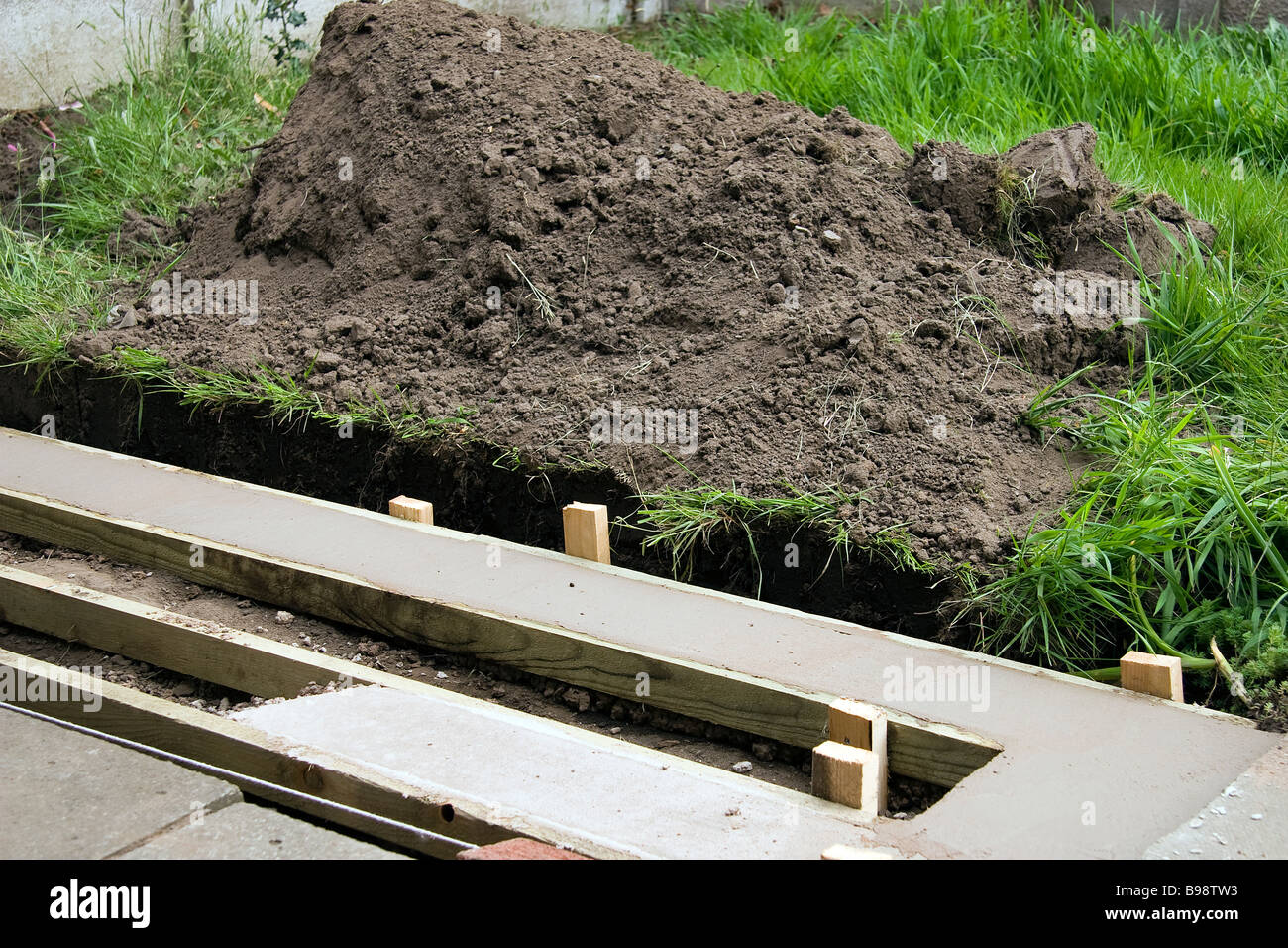 Two parallel rows of footings nearly complete in front of a mound of ...