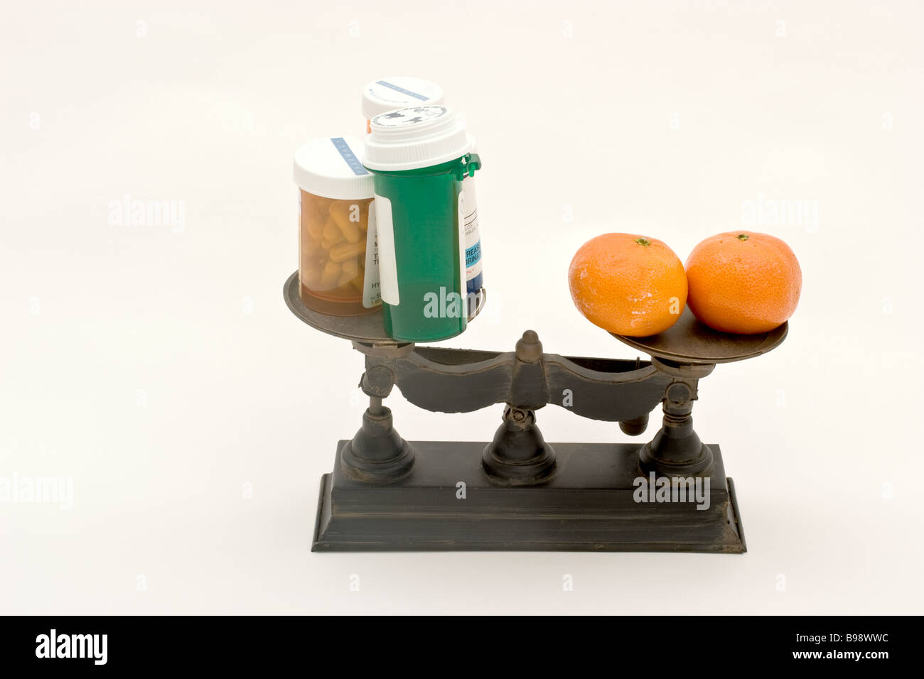 Balance scale with oranges on one side and prescription containers on ...