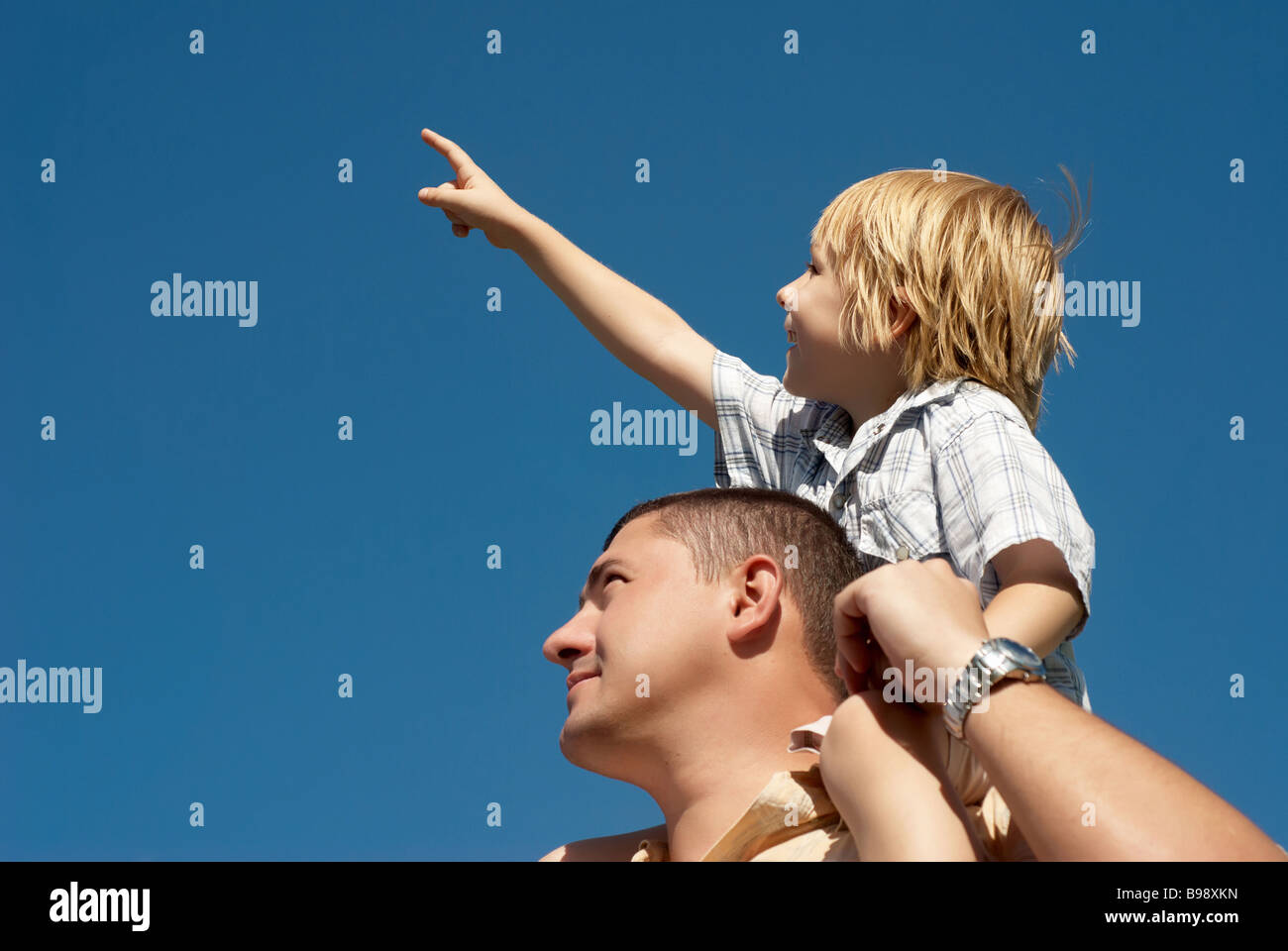 younger brother younger on shoulders at senior brother against the sky ...
