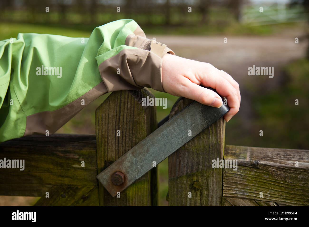 Womans hand opening closing metal latch on timber gate in the ...