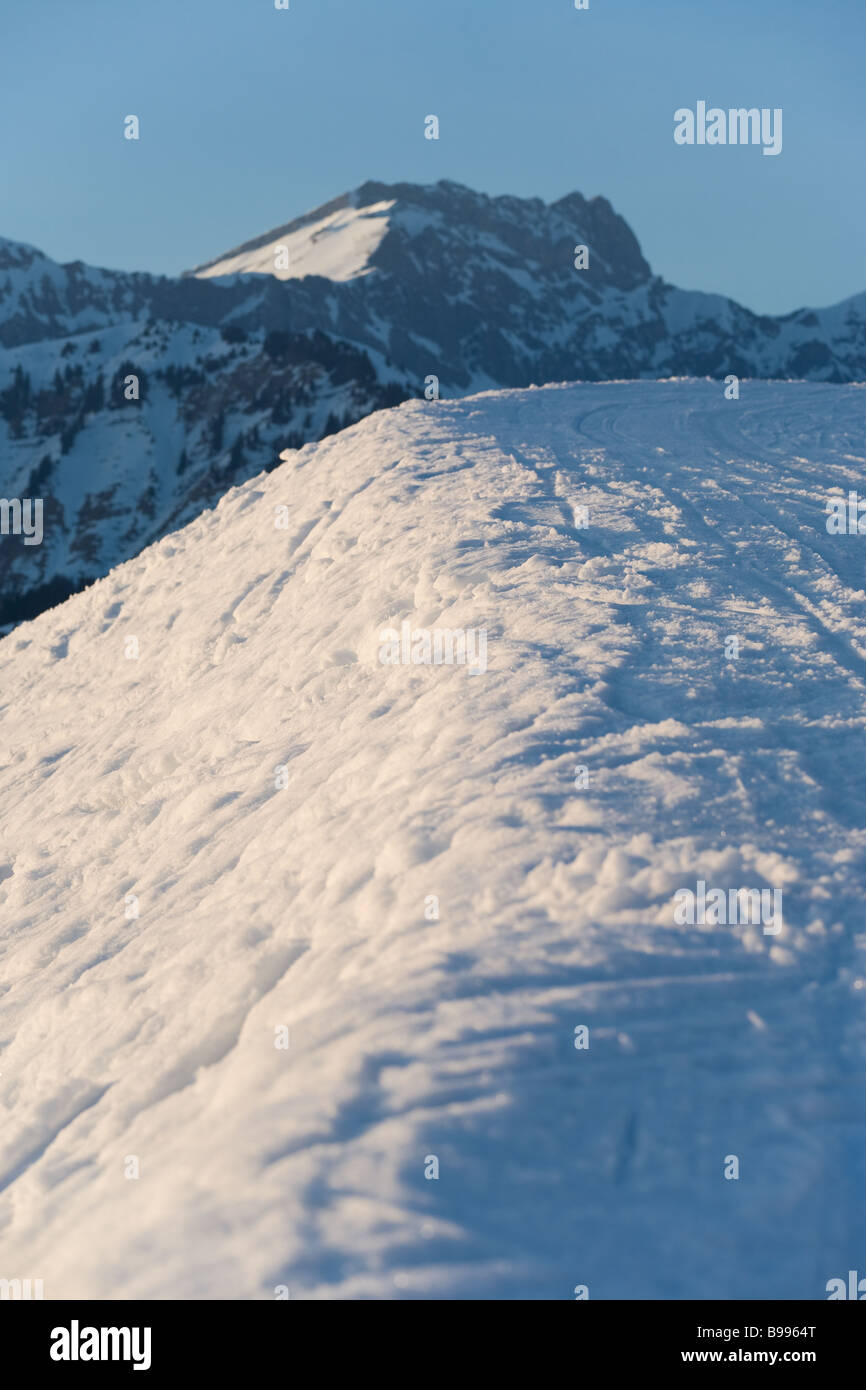 Ski tracks along an icy ski slope dropoff in the foreground and a chain ...