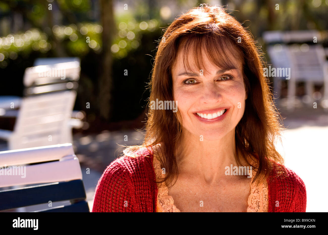 Woman portrait aged 50s in red with sunshine and smile laughing and ...