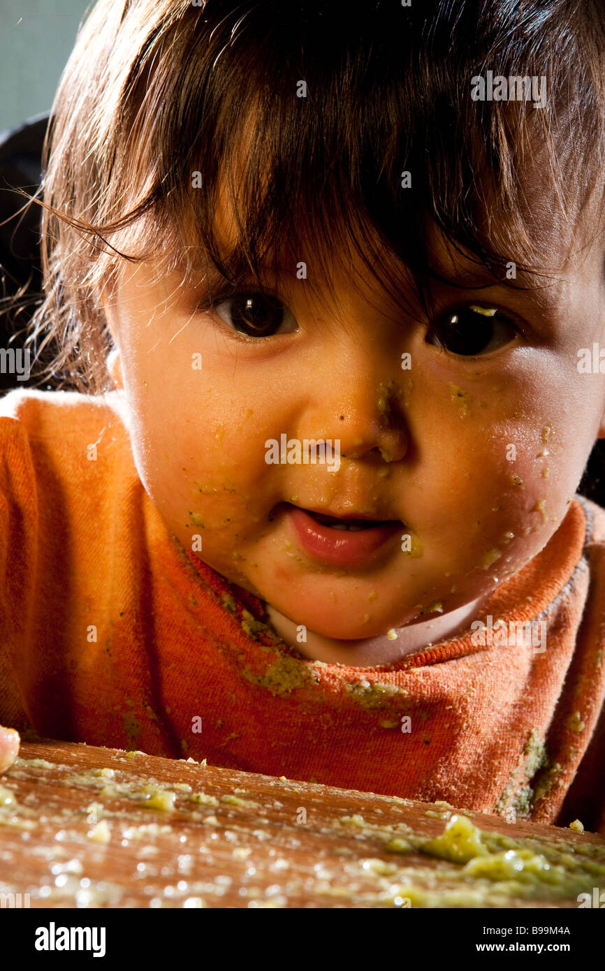 A nine month old baby eating and making a giant mess at the kitchen ...