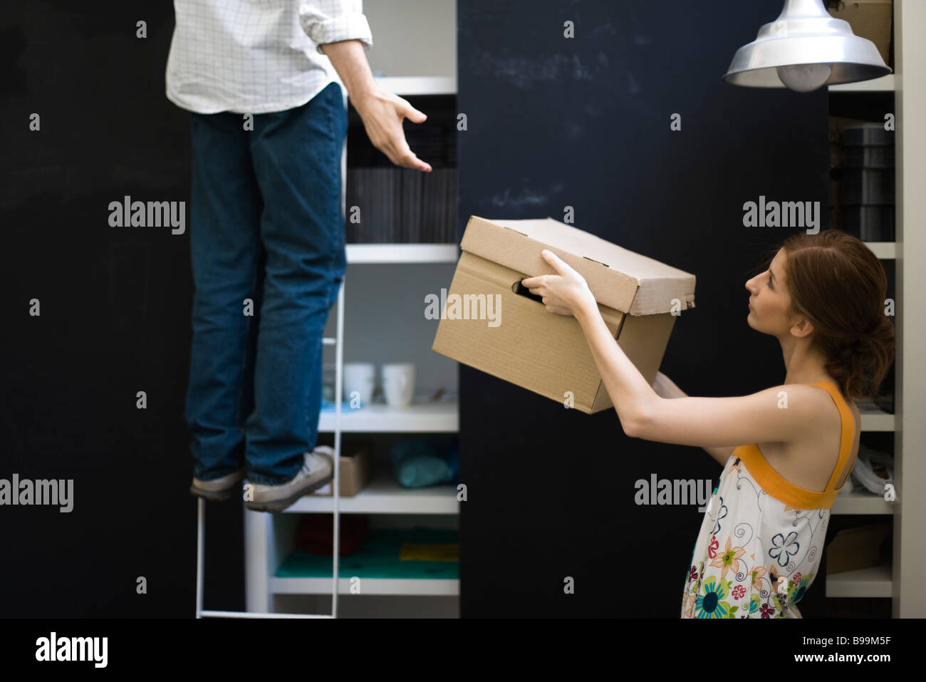Woman handing box to man standing on ladder Stock Photo - Alamy