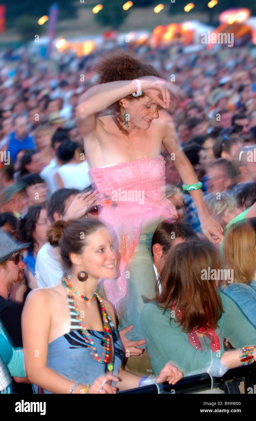 Girl dancing on the shoulders of her friend in the crowd at a Festival ...