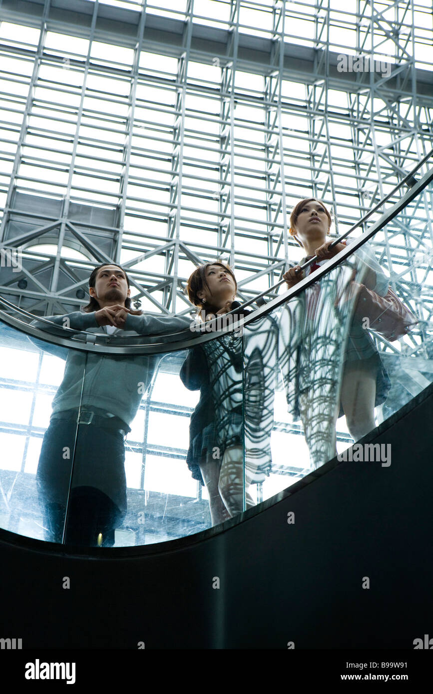Friends leaning against railing, looking up, low angle view Stock Photo ...