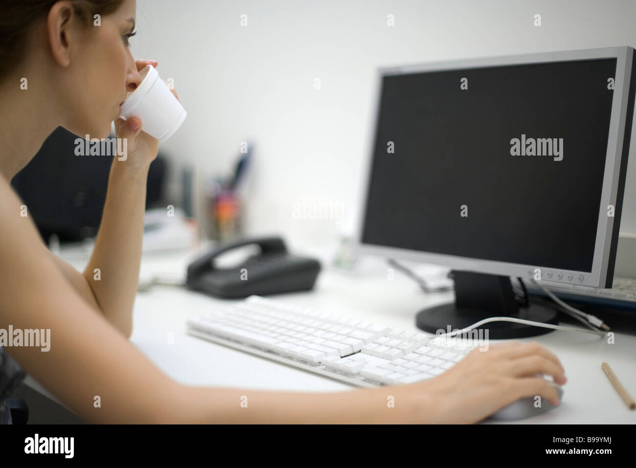 Woman working at desk, drinking from disposable cup Stock Photo - Alamy