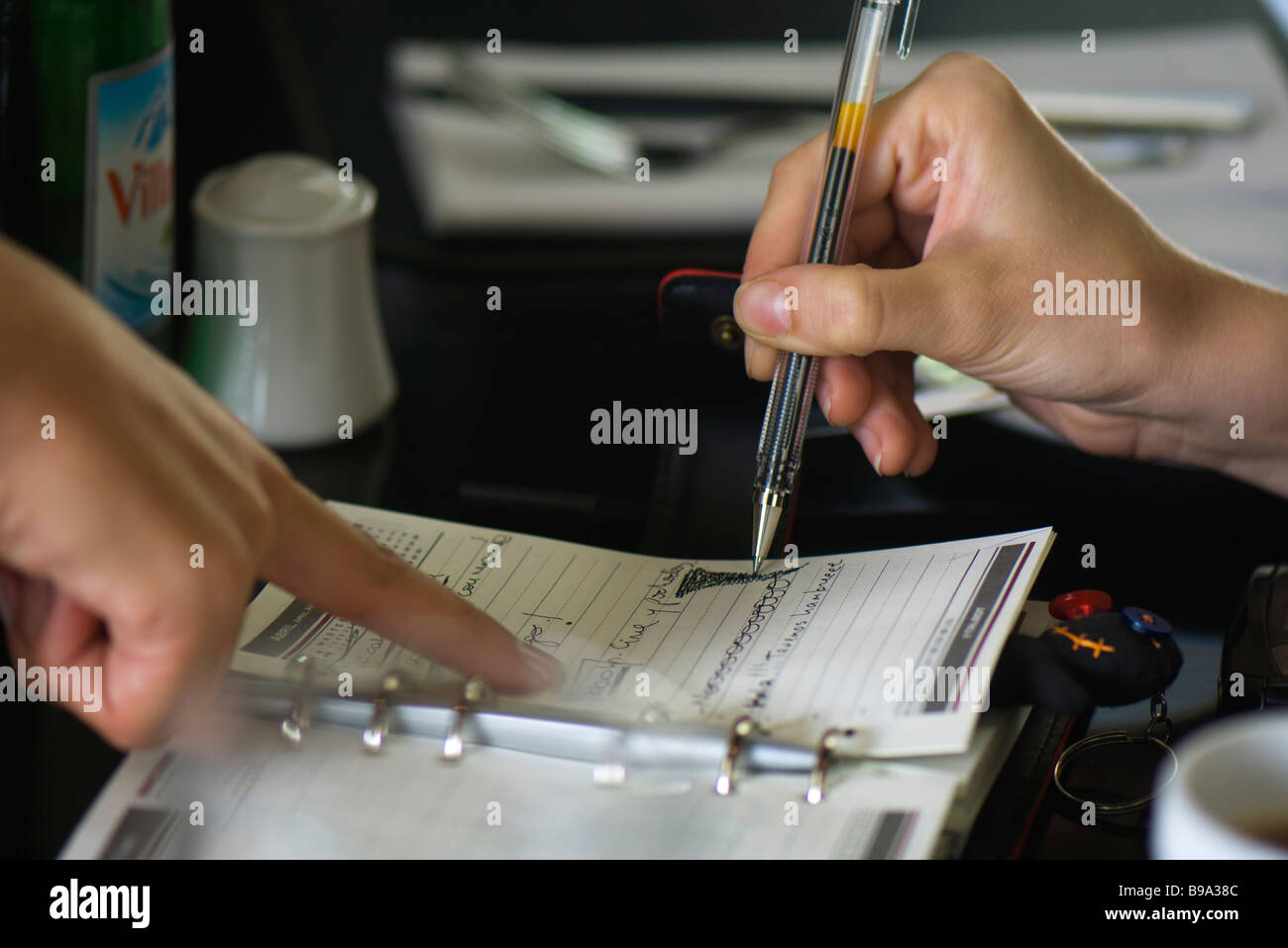 Two people making plans using agenda, one holding pen while the other ...