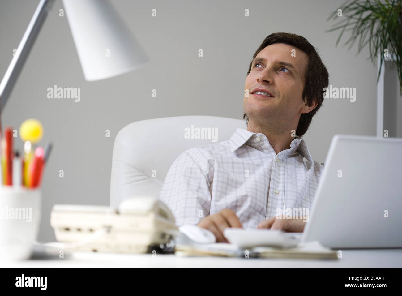 Man sitting at desk, looking up Stock Photo - Alamy