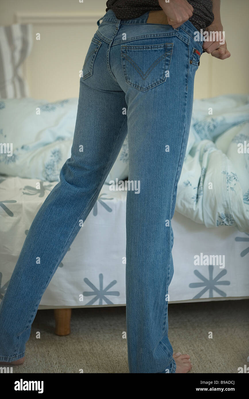Woman putting on snug-fitting jeans, cropped view Stock Photo - Alamy