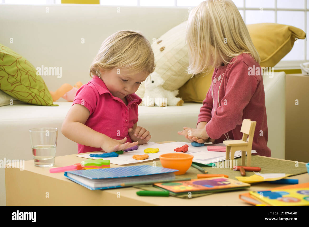 Little girls playing with clay on coffee table Stock Photo - Alamy