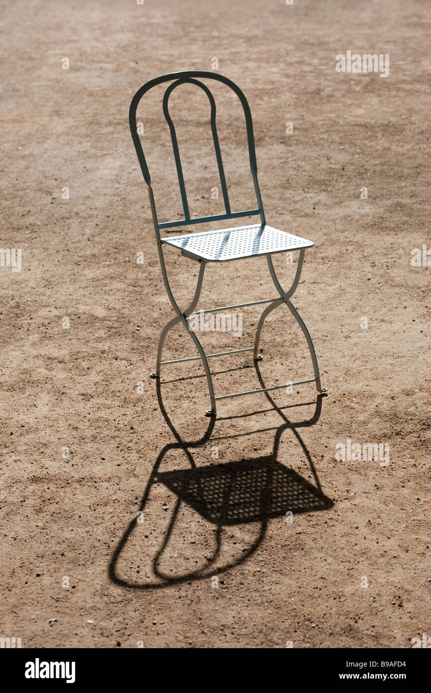 A decorative steel chair casts a shadow on the ground Stock Photo - Alamy