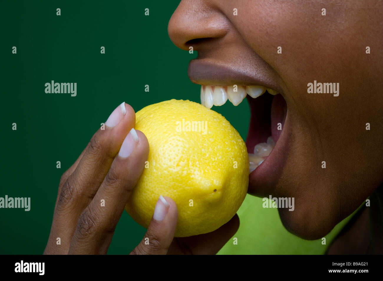 Close up of woman biting lemon Stock Photo - Alamy