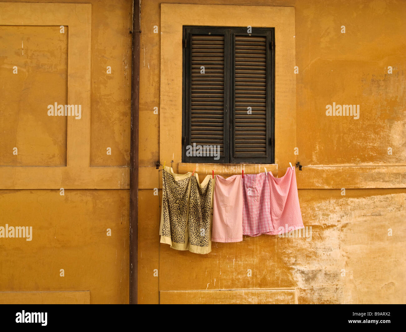 Washing hanging below shuttered window against weather worn wall Rome ...