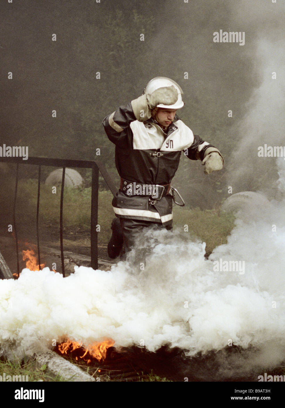 Firefighter in protective clothes surmounting the obstacles during the ...