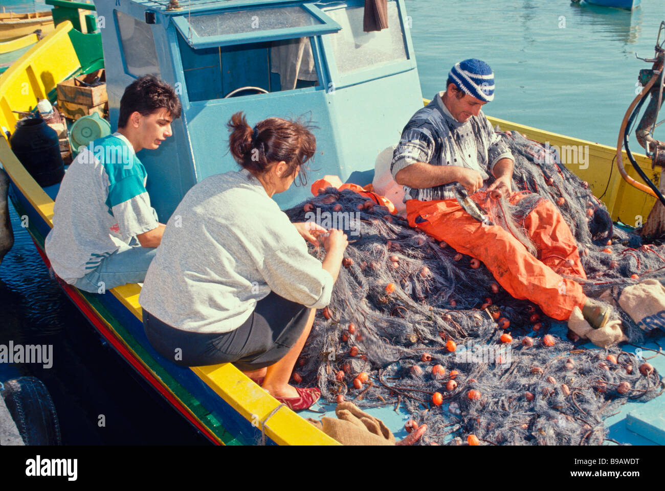 Cleaning fishing nets aboard a luzzu inshore fishing boat Malta Maltese ...