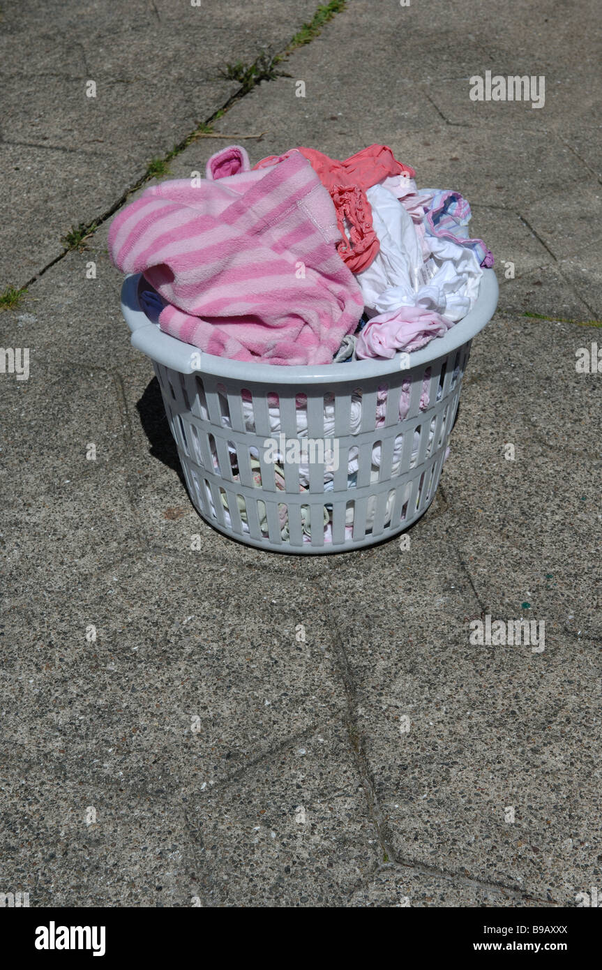 A plastic basket of washing on a concrete garden patio Stock Photo - Alamy