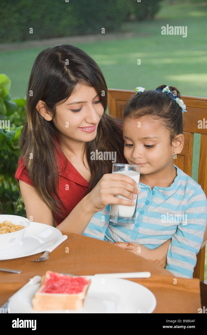 Girl drinking milk from a glass held by her mother Stock Photo - Alamy