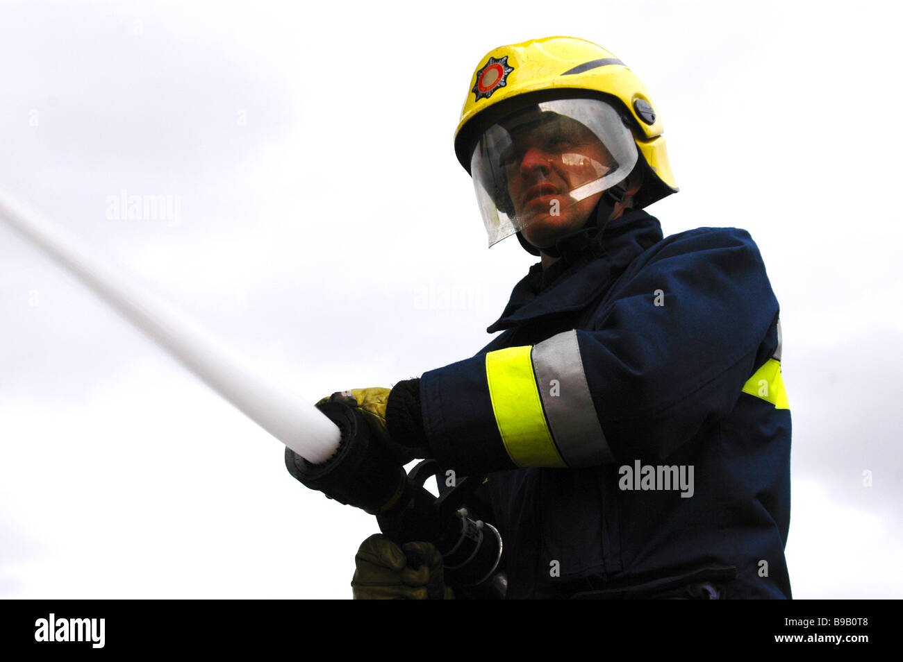 A Fire-fighter using his hose Stock Photo - Alamy