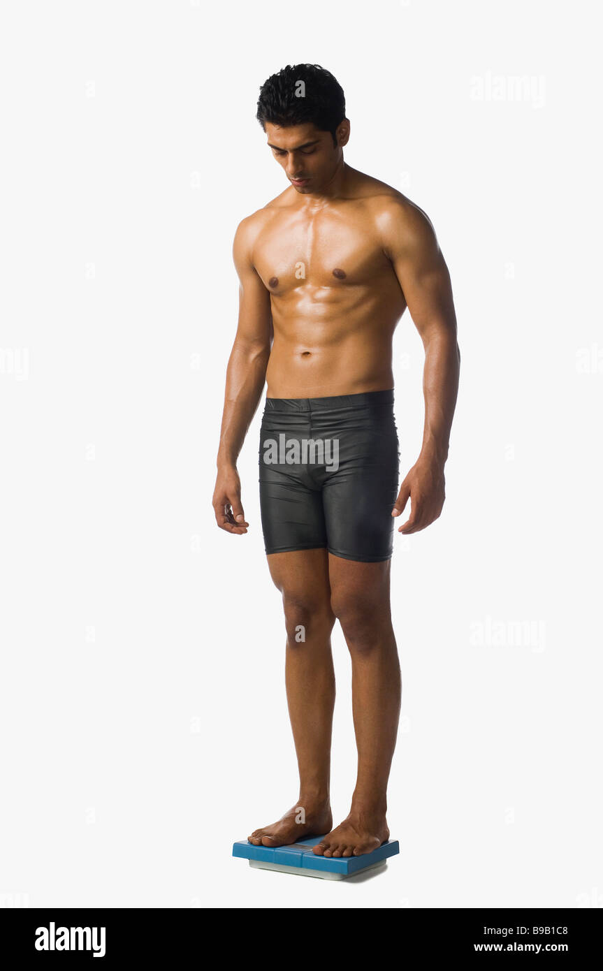 Man measuring his weight on a weighing scale Stock Photo - Alamy