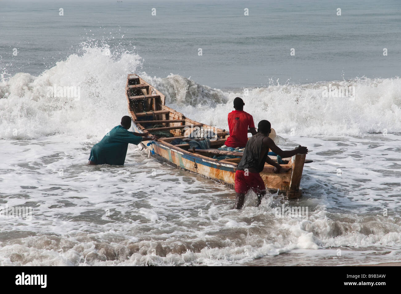 West Africa Ghana Cape Coast Fishermen pushing their fishing dugout ...