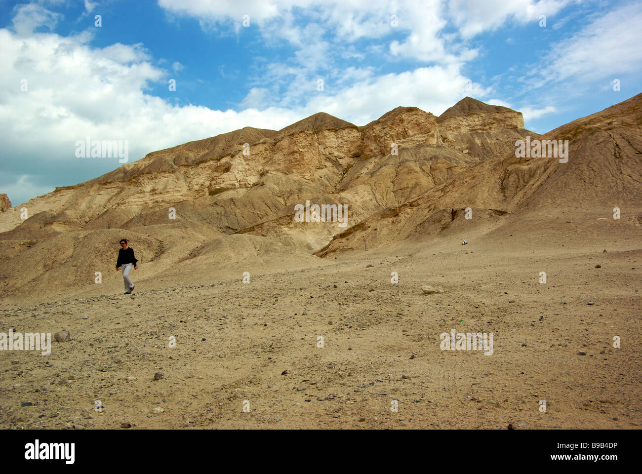 Woman walking down hiking trail from barren ridge on the desolate ...
