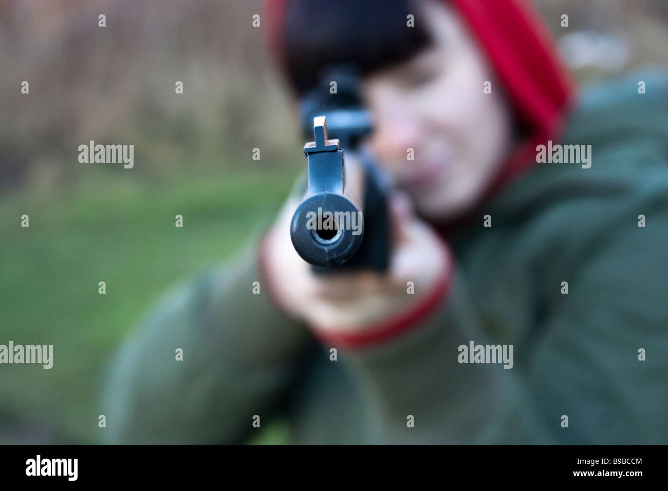 Young blurry person aim a rifle into the camera Stock Photo - Alamy