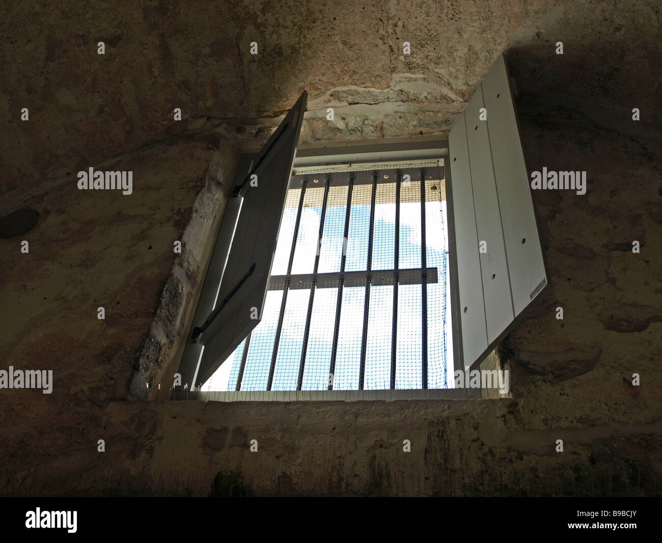 window inside of old fort with shutters stone wall and bars with clouds ...