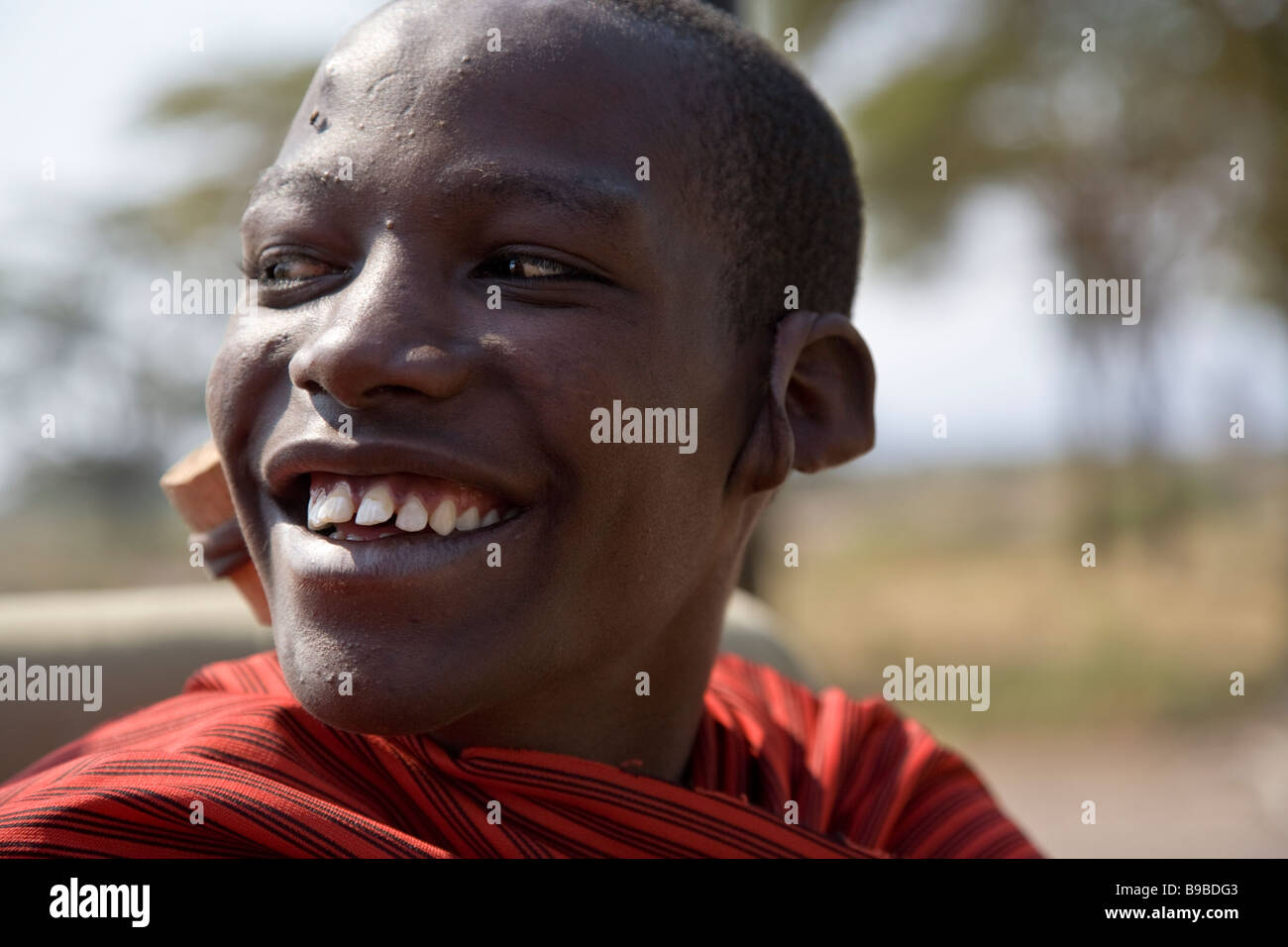 Portrait of Maasai male smiling with large wooden ear plug in one ear ...