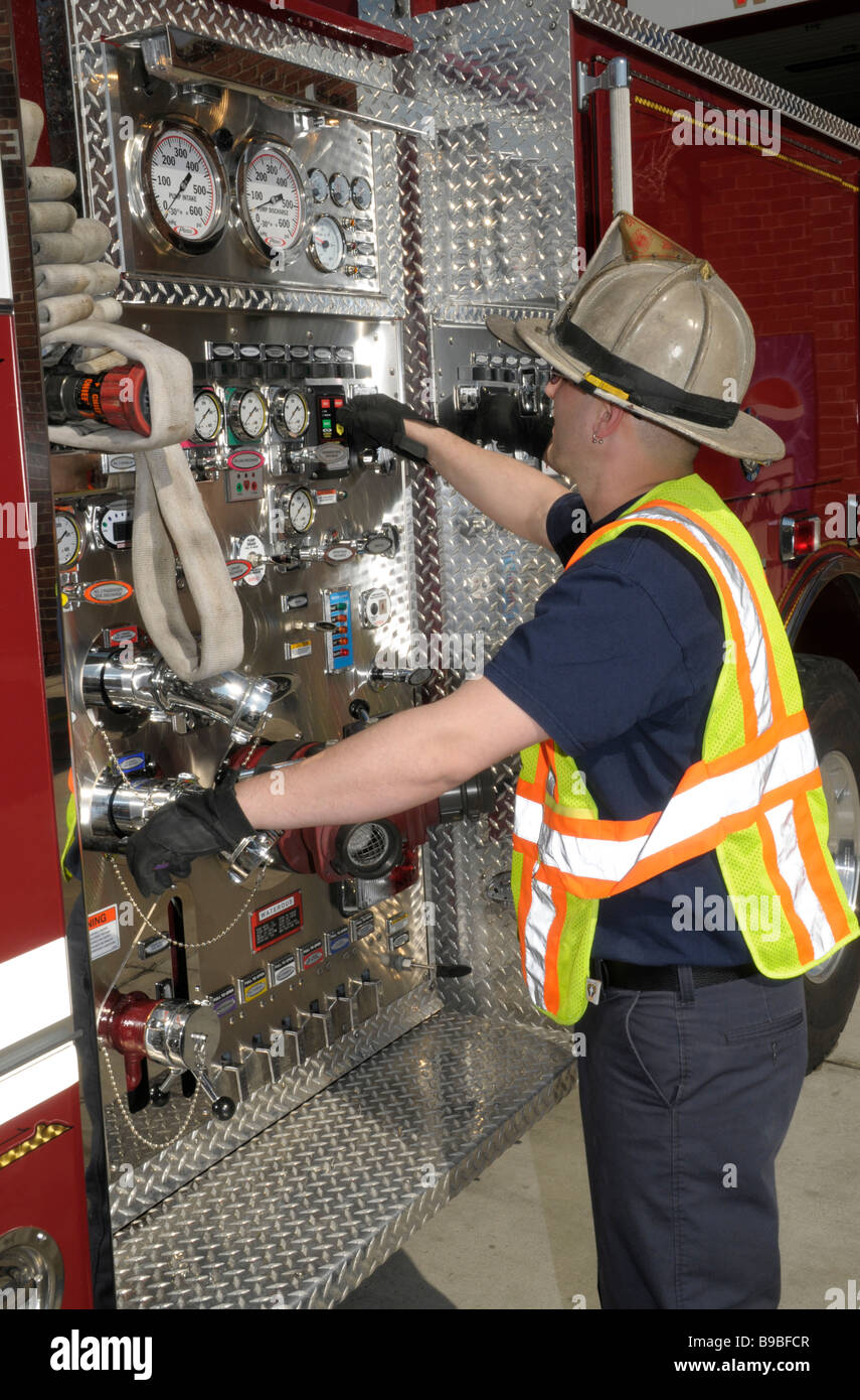 firefighter operating the pump panel on a fire truck at the scene of a ...