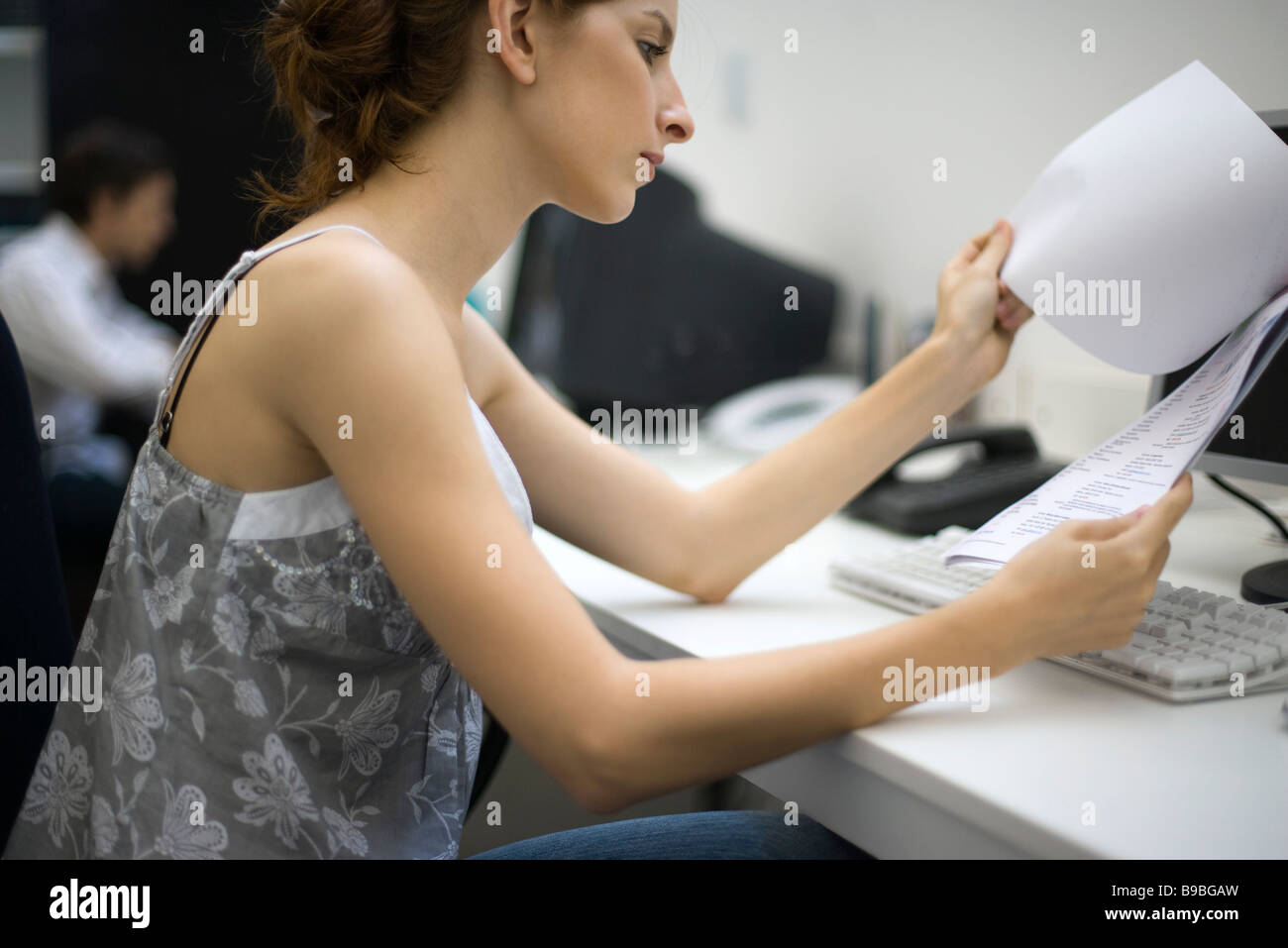 Casually dressed woman reading document at desk Stock Photo - Alamy