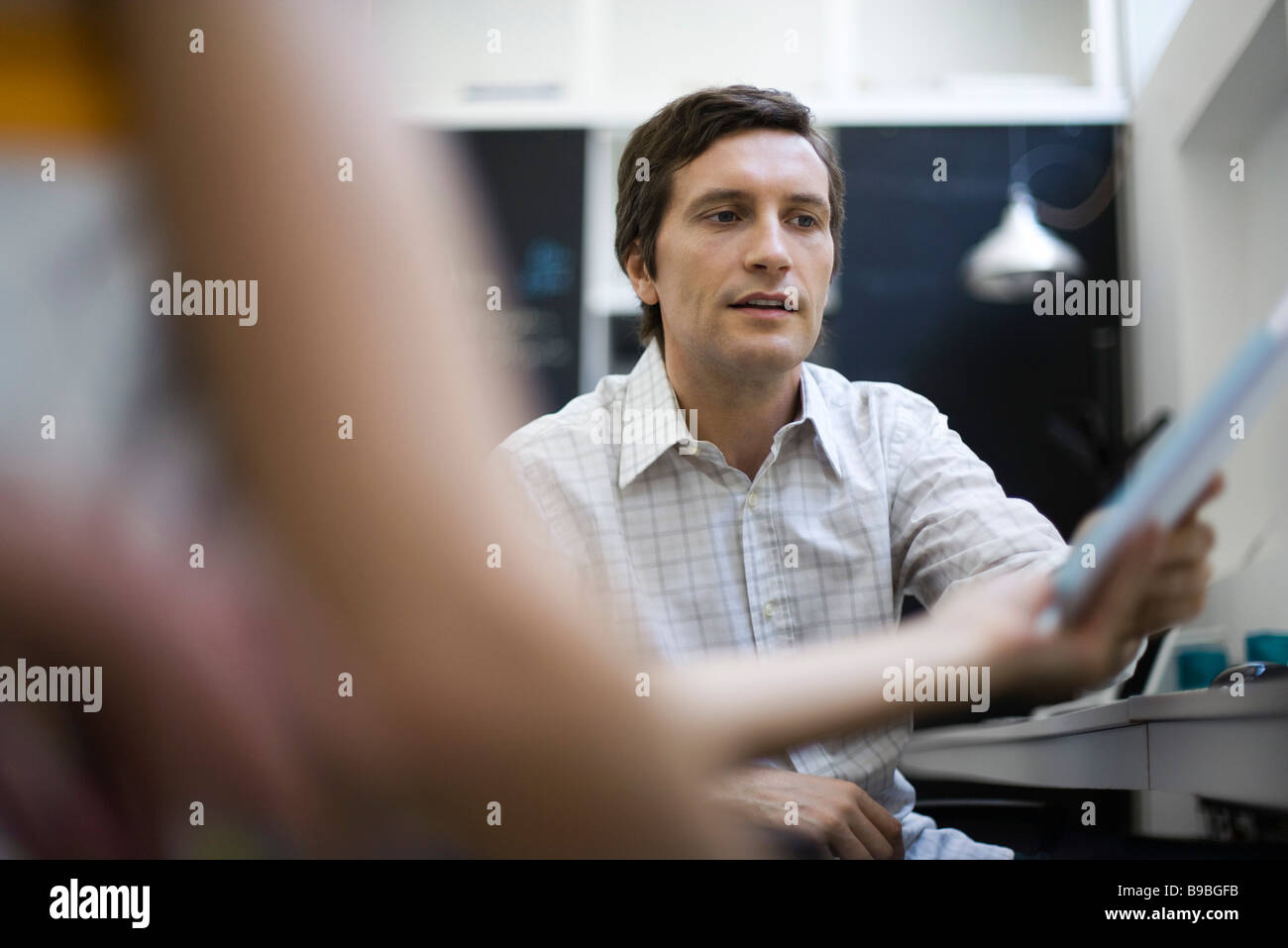 Man receiving document from colleague Stock Photo - Alamy