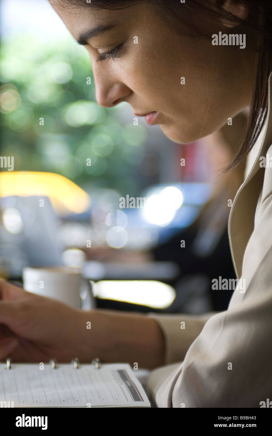 Woman sitting in cafe, looking at agenda, close-up Stock Photo - Alamy