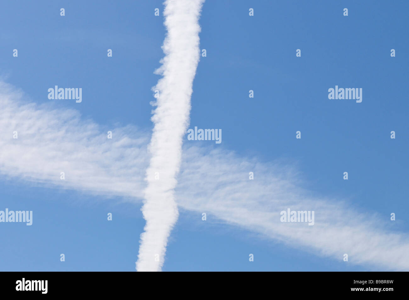 Two contrails cross in a blue sky Stock Photo - Alamy