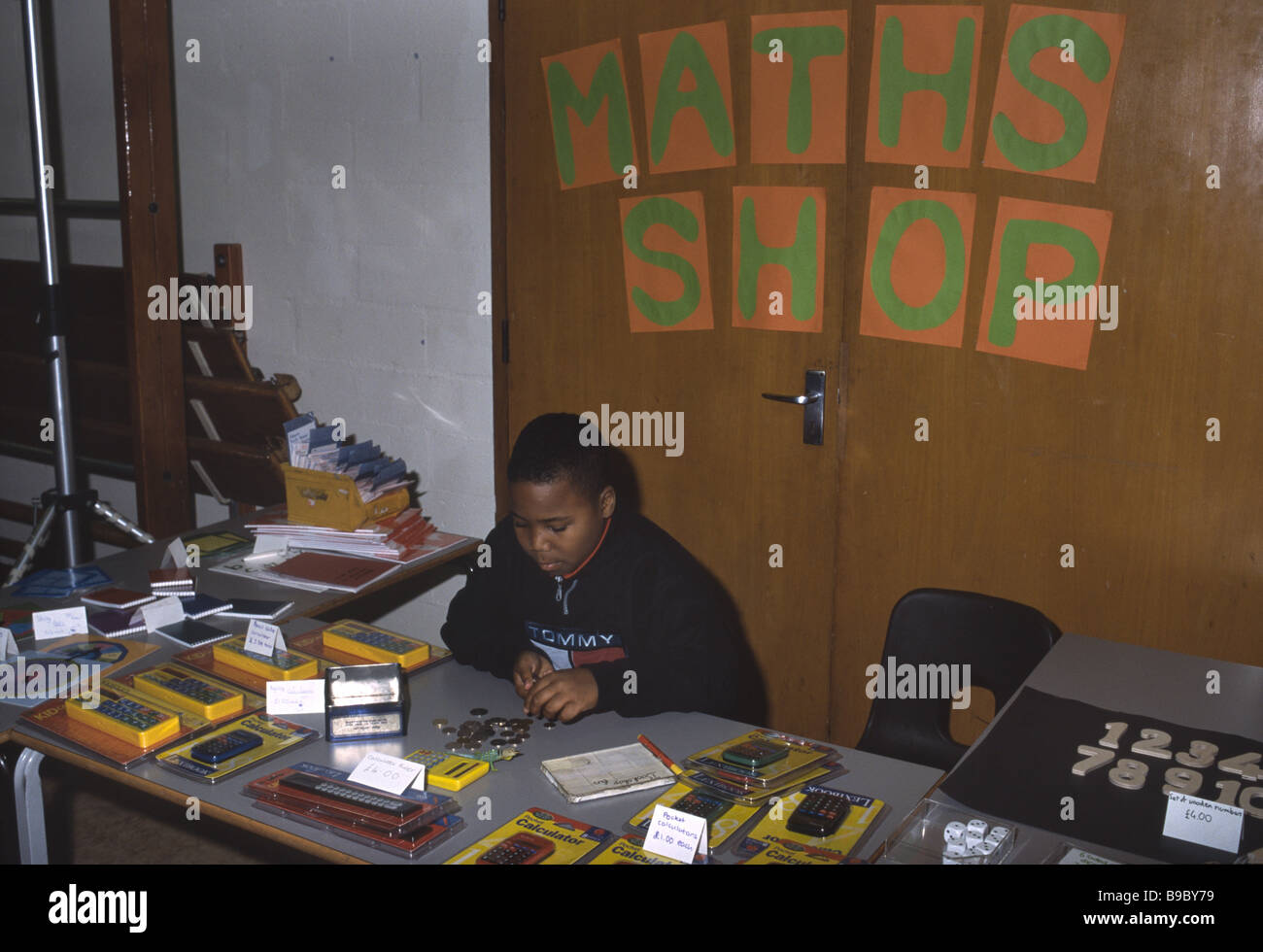 Black Afro-Caribbean boy counting money in a primary school classroom ...