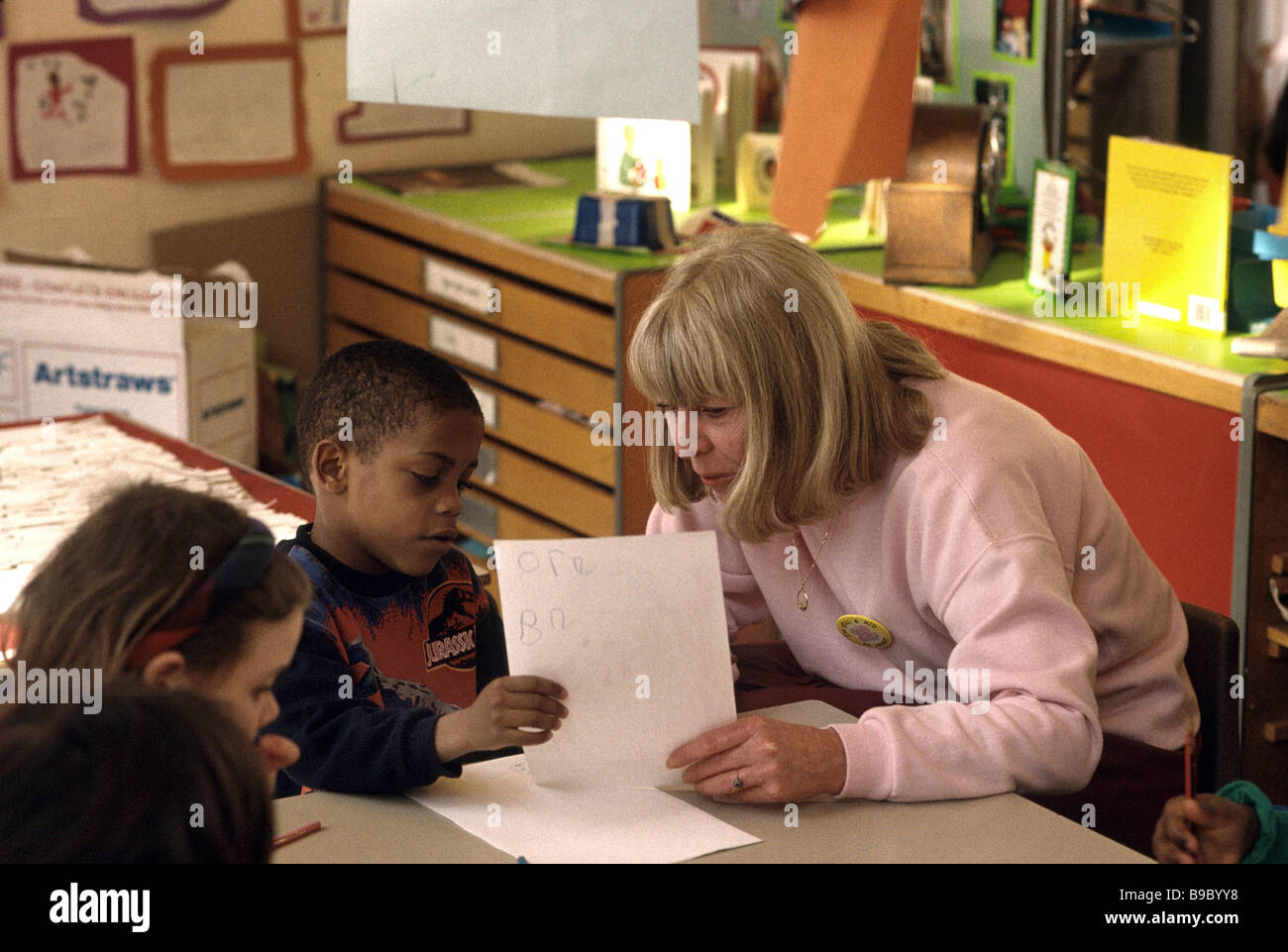 teachers assistant helping a young nursery school boy write Stock Photo ...