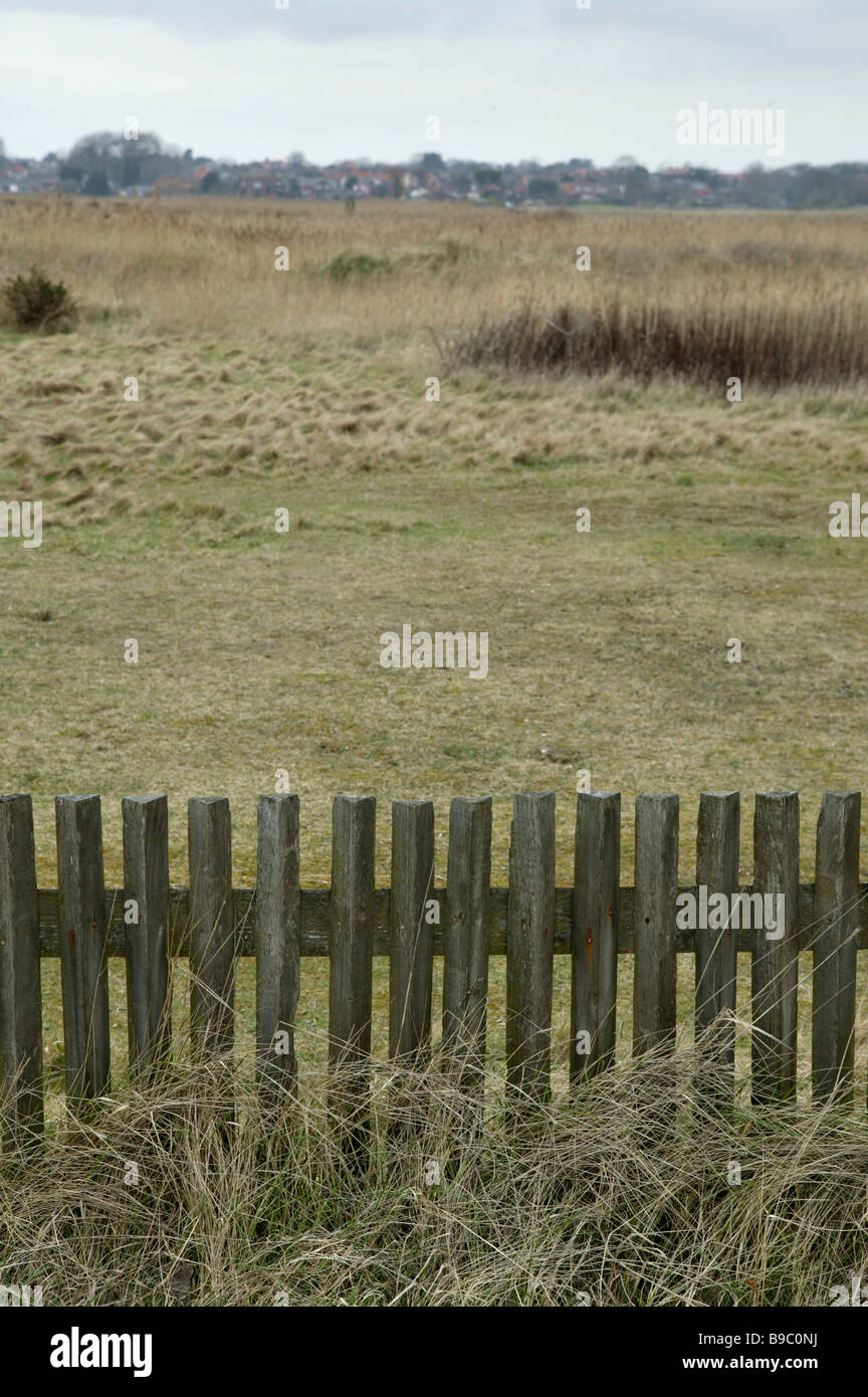 a wooden picket fence in front of open coastal marshland in east anglia ...