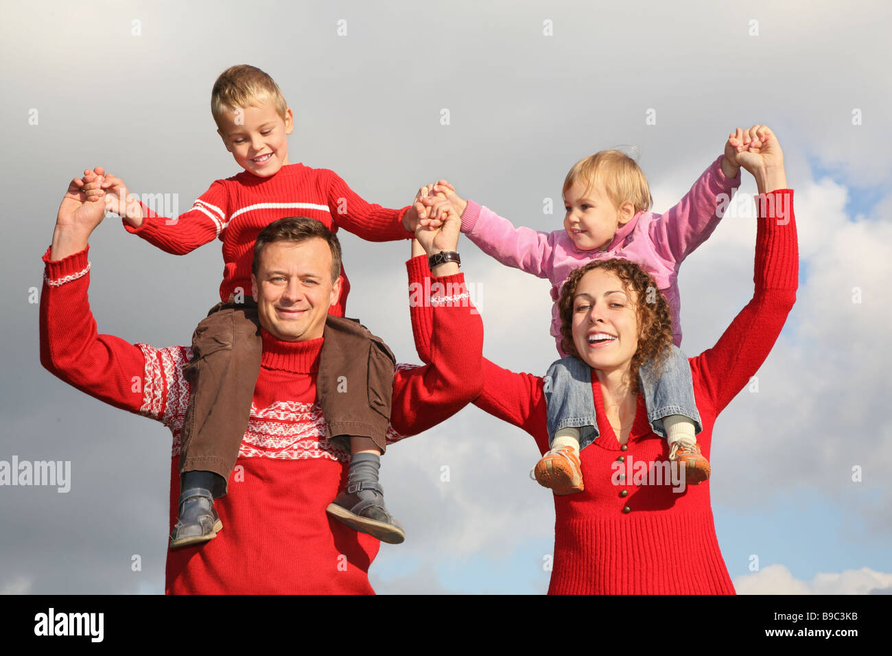 father and mother stand, holding children on the shoulders Stock Photo ...