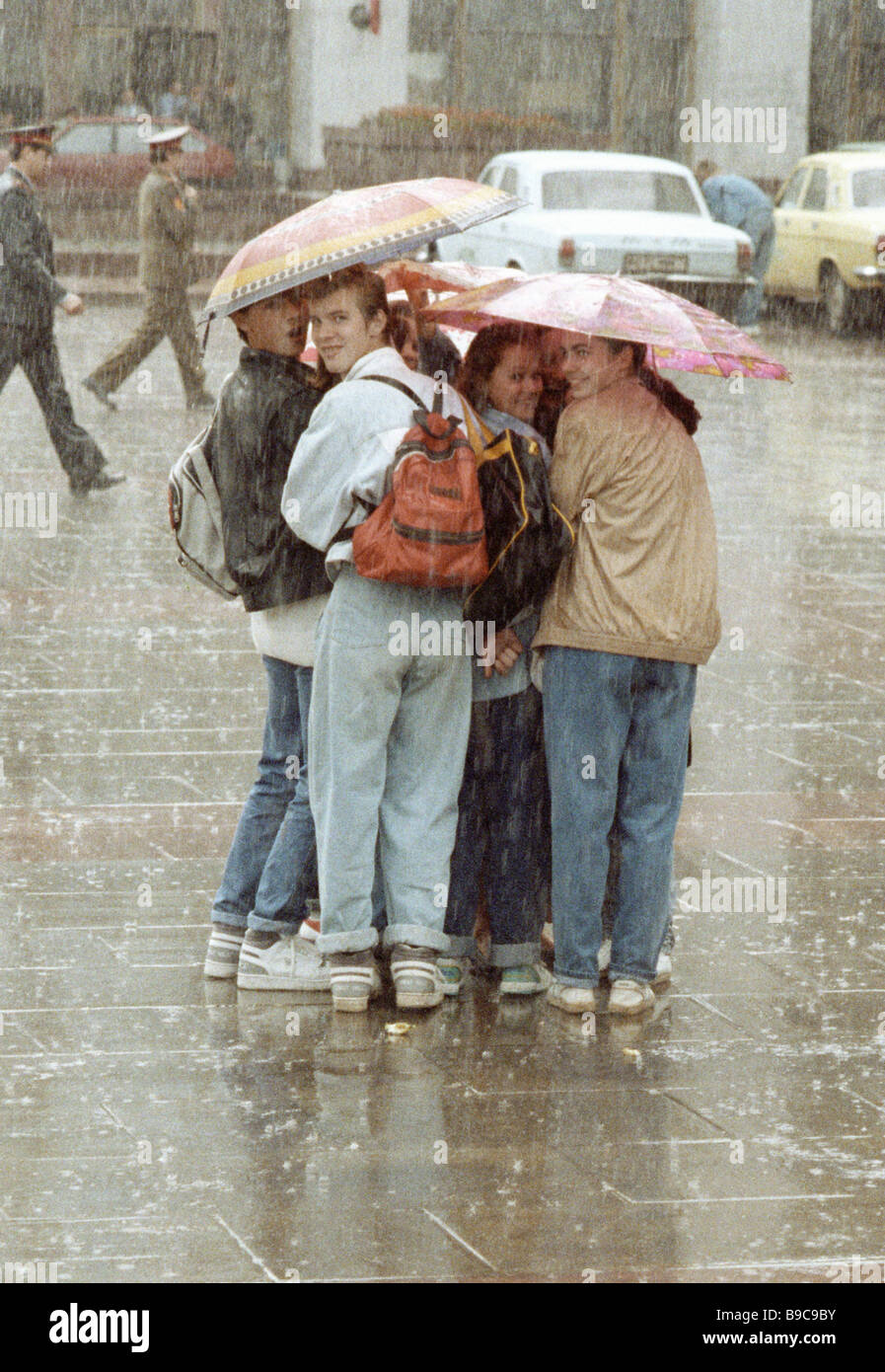 Young people hiding under umbrellas Stock Photo - Alamy