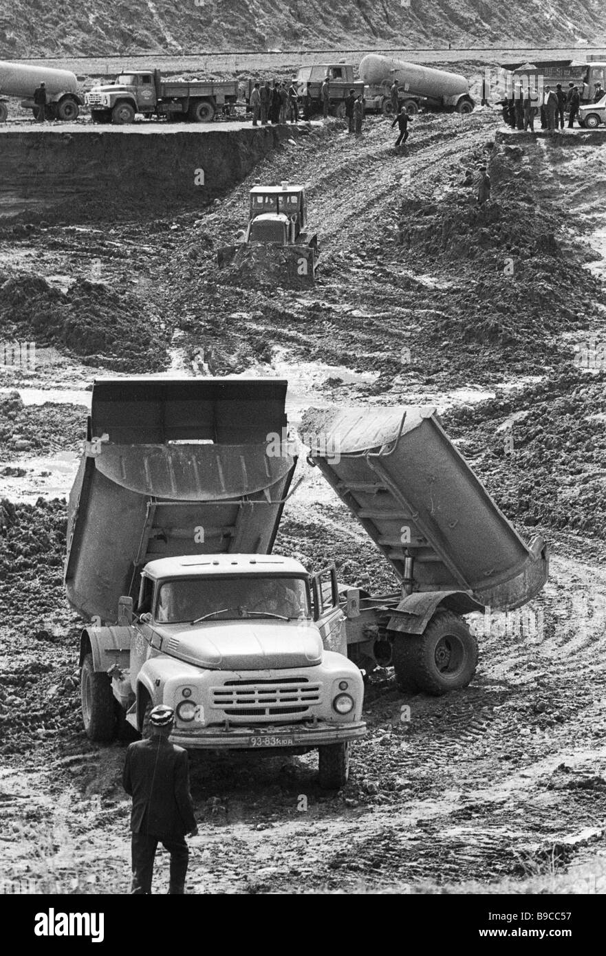 Dump trucks and road machinery restoring the road damaged by the ...